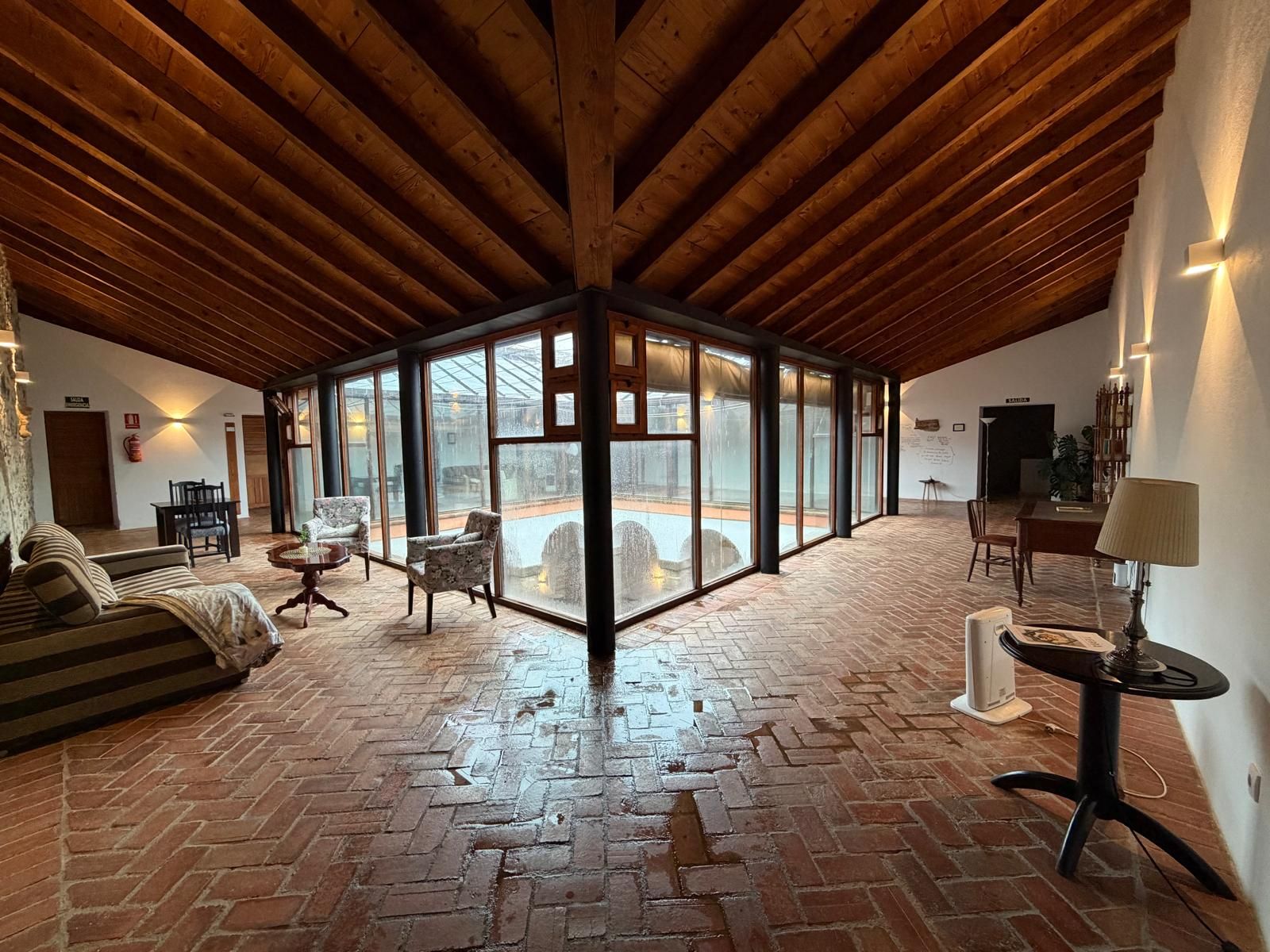 Um quarto espaçoso com teto alto, janelas amplas e piso de tijolos.