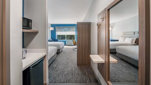 Quarto de hotel com cama, secretária, micro-ondas e janela com vista.