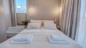 Quarto de hotel com uma cama grande, duas mesas de cabeceira e uma janela com cortinas.