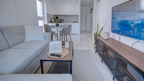Uma sala de estar moderna com um sofá, uma mesa de centro e uma TV sobre um suporte.