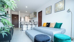 Uma sala de estar moderna com um sofá, pufes e um espaço de jantar com cadeiras.