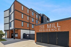 Um edifício moderno de vários andares com uma placa de destaque que diz "The Mill Residence".