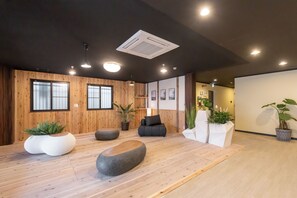 Interior moderno com paredes de madeira, teto preto e balcão de recepção com plantas.