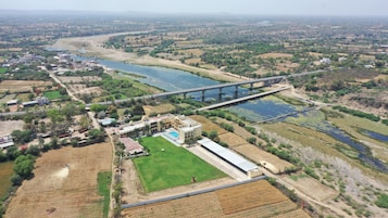 Vista aérea de uma cidade com uma ponte notável, campos verdes e um edifício grande com piscina.
