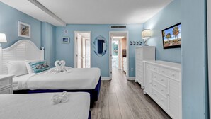 Quarto com duas camas, uma cômoda e uma televisão.