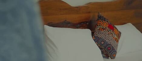 Cama com cabeceira de madeira e travesseiro estampado.