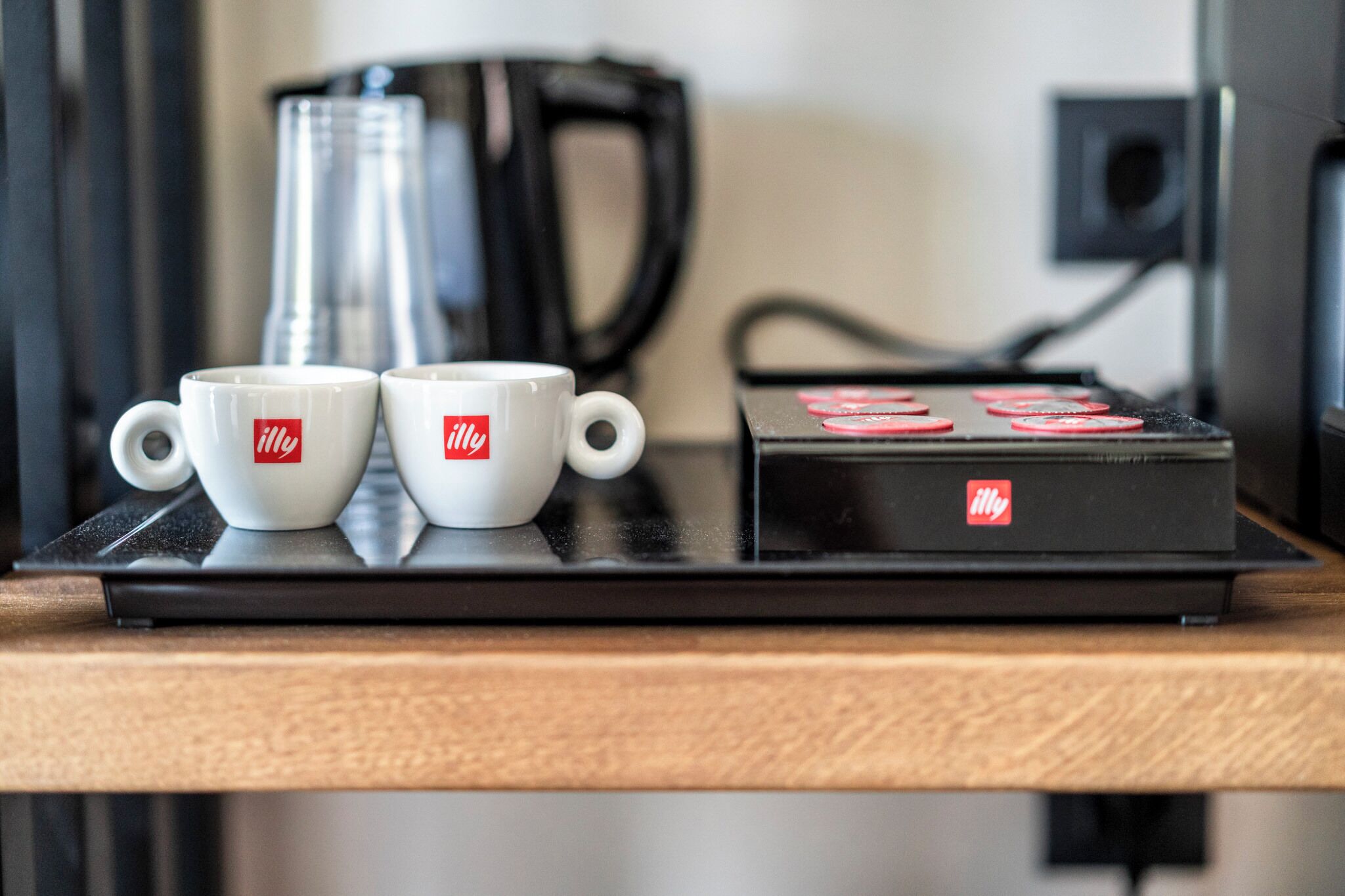 Uma máquina de café e duas chávenas sobre um tabuleiro.
