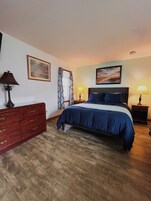 Quarto com cama, penteadeira, duas mesinhas de cabeceira e duas luminárias.