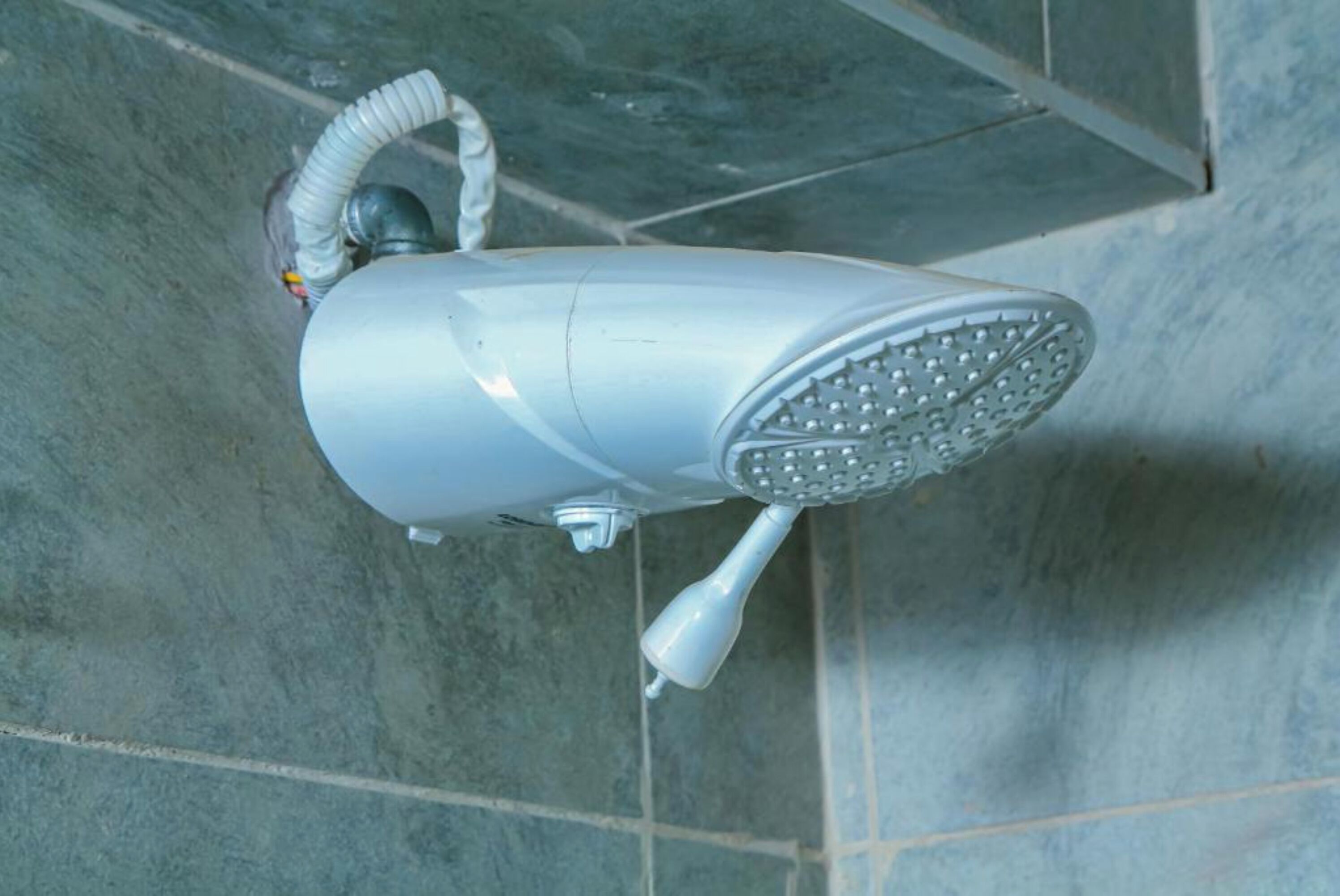 Secador de cabelo fixado no teto, com mangueira flexível, instalado em um ambiente revestido com azulejos.