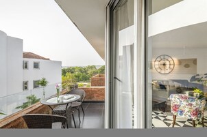 Varanda com mobiliário de vime, uma mesa e uma cadeira.