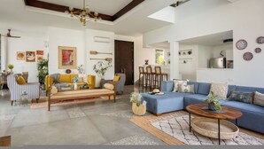 Uma sala de estar ampla com um sofá azul, uma mesa de centro de madeira e uma área de jantar com cadeiras e uma mesa.