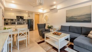 Uma sala de estar moderna com um sofá cinzento, uma mesa de centro branca e um espaço de jantar com cadeiras e mesa brancas.