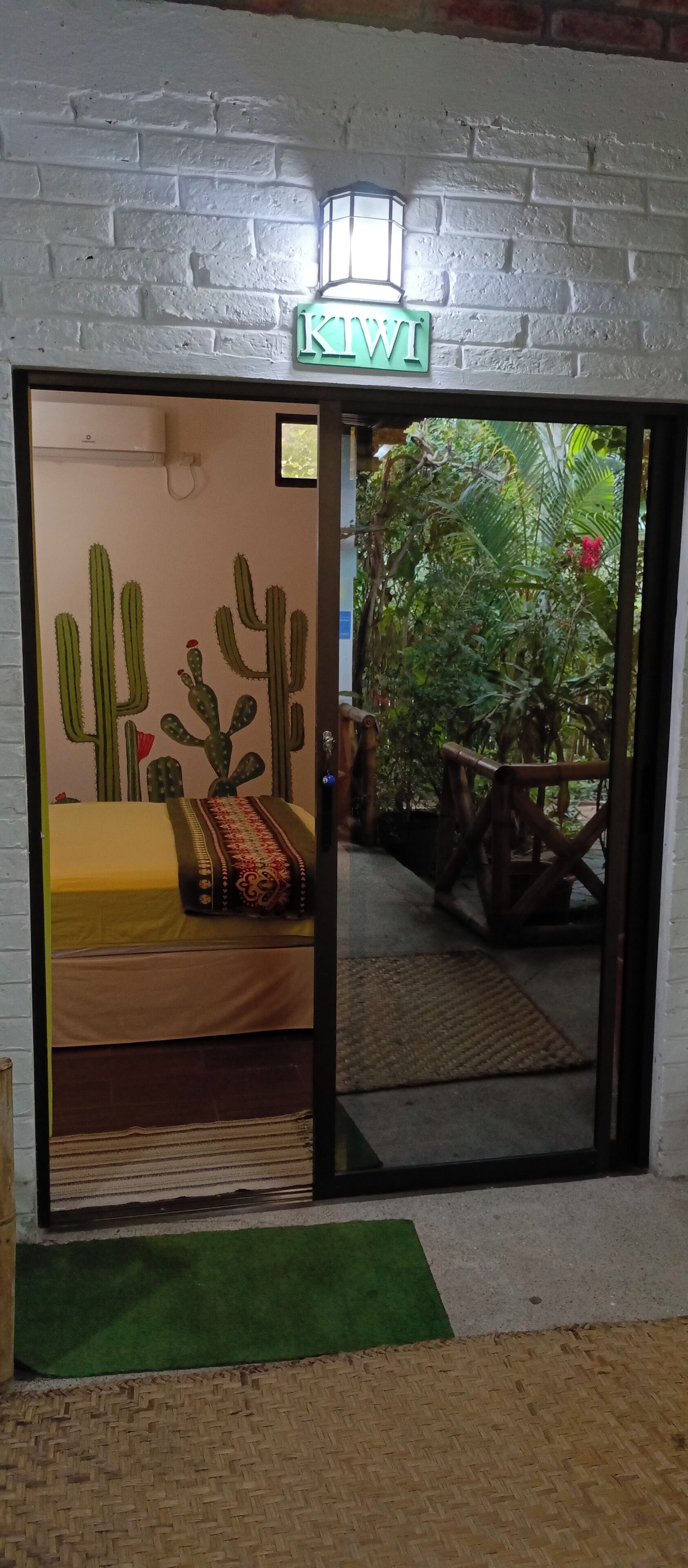 Um quarto com uma cama, um tapete verde e arte de parede com cactos.