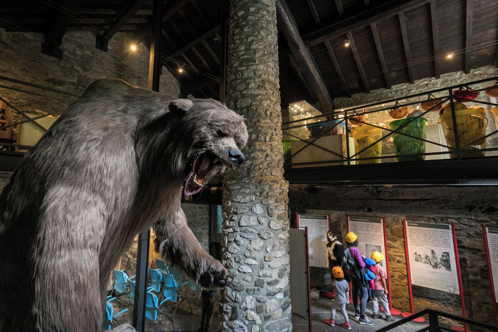 Uma grande estátua de urso em um museu, com pilares de pedra e exposições.