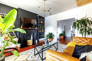 Sala de estar com lareira, sofá, mesa de centro e várias plantas.