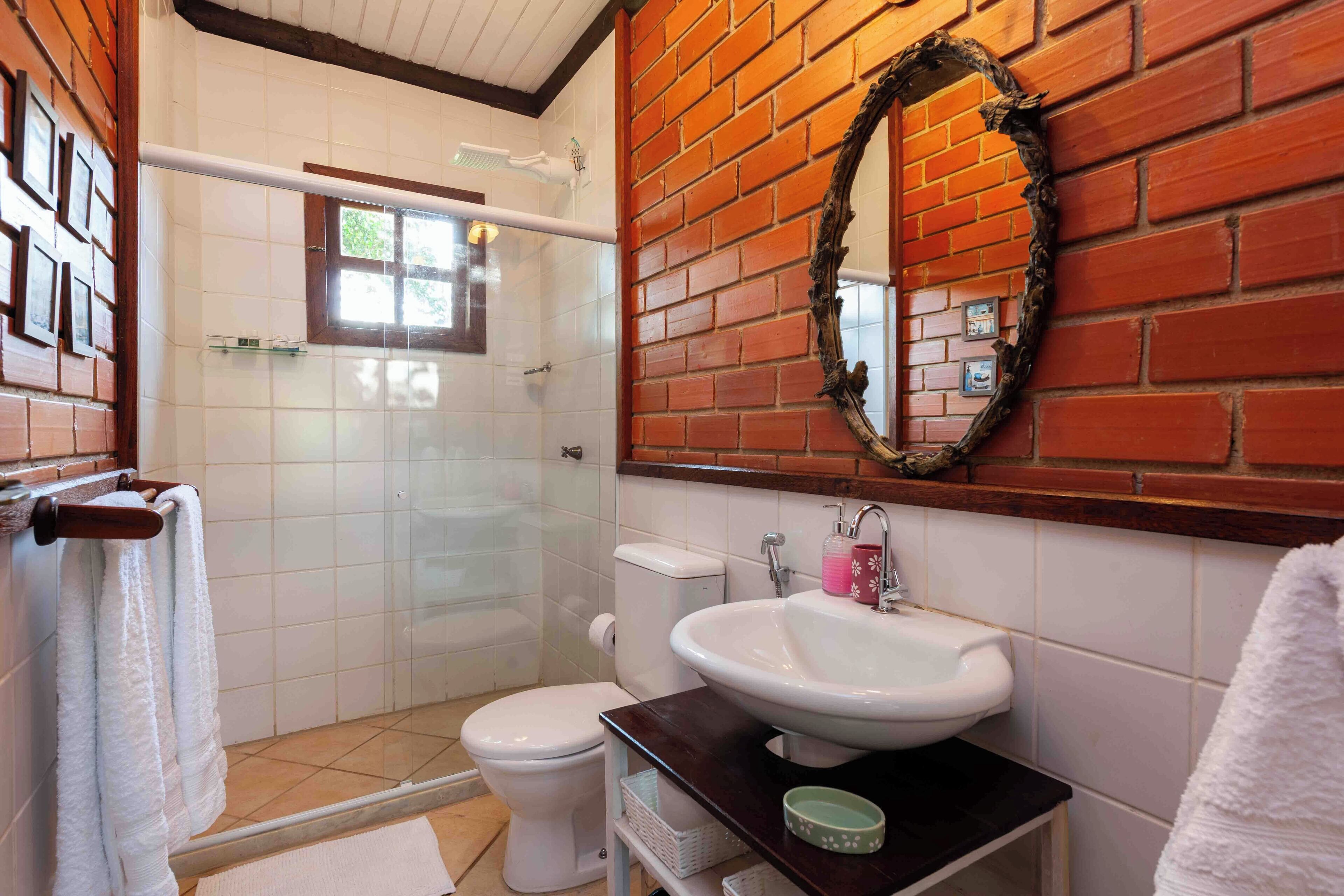 Casa de banho com sanita, lavatório e chuveiro.