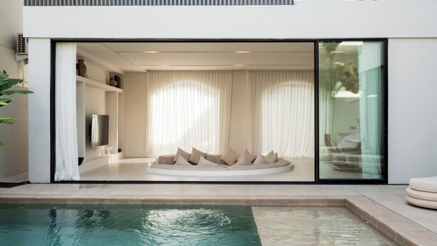 Um interior moderno com uma área de estar circular, piscina e porta de vidro que dá para uma varanda.