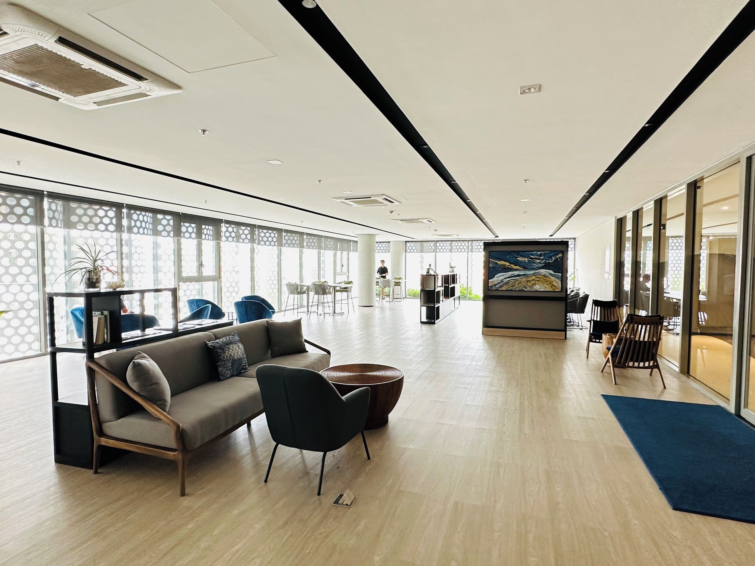 Um hall amplo com um sofá, cadeiras, uma mesa de centro e uma pintura grande na parede.