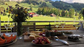 Mesa posta com comida e bebidas, com vista para uma paisagem montanhosa.