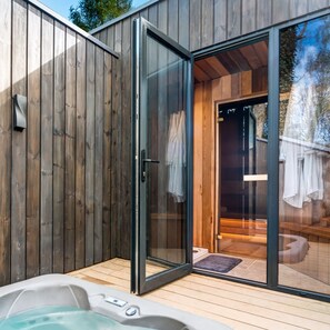 Uma cabana de madeira com uma porta de vidro que dá para um espaço de pátio.