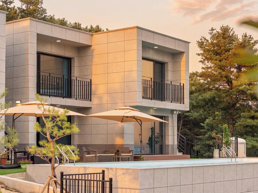 Um edifício moderno de vários andares com varandas, área de estar ao ar livre e piscina.