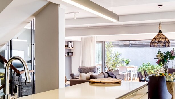 Uma cozinha moderna com uma ilha grande, uma área de jantar com mesa e cadeiras, e vista para o exterior.