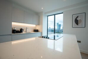 Uma cozinha moderna com uma ilha grande, vista para a cidade e armários minimalistas.