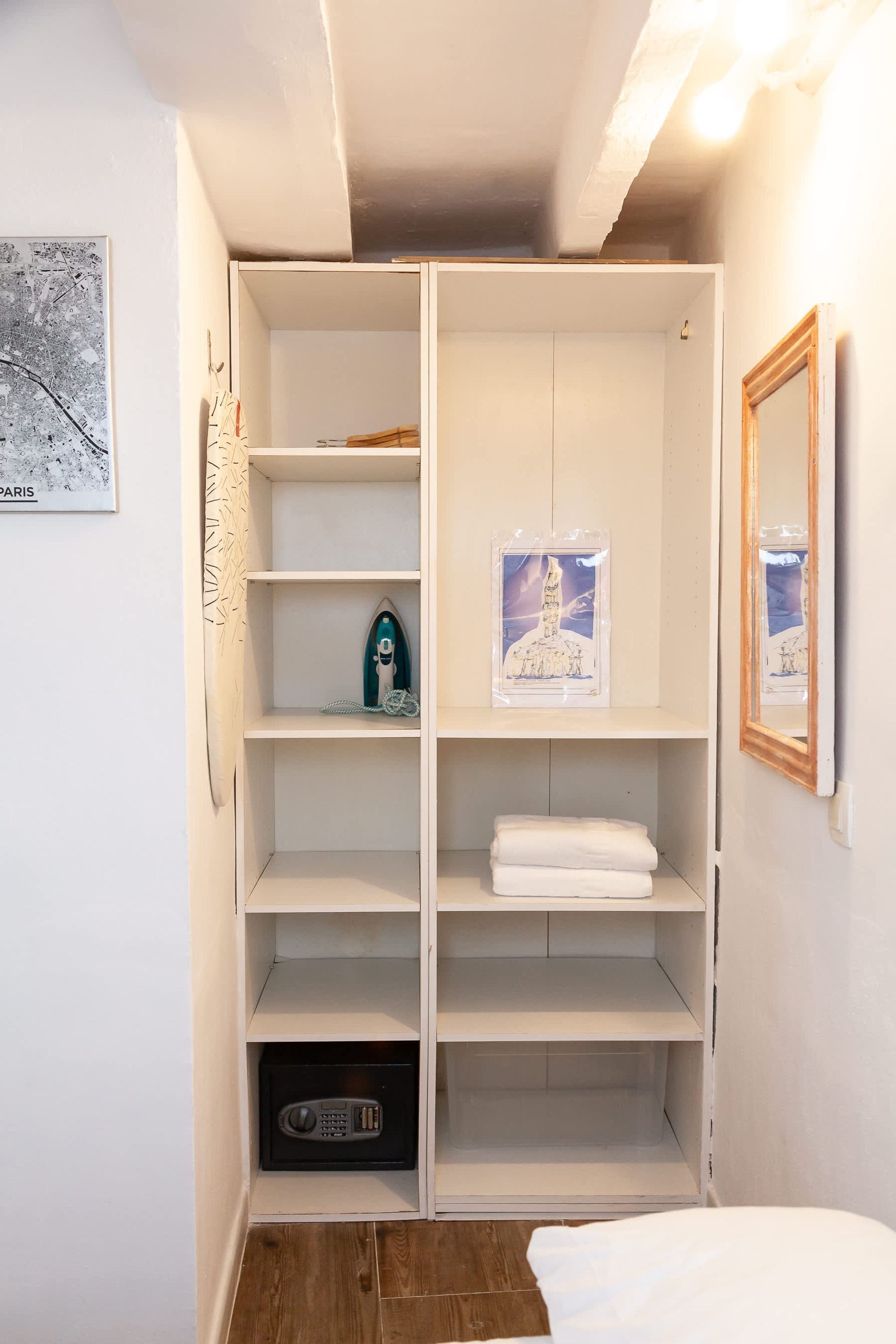 Um closet amplo com prateleiras, um quadro emoldurado e um espelho.