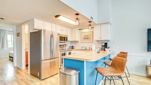Uma cozinha moderna com eletrodomésticos de aço inoxidável, uma ilha azul e banquetas.