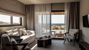Uma sala de estar moderna com sofá, poltronas, mesa de centro e vista para o mar.