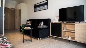 Uma sala de estar moderna com um sofá preto, uma mesa de centro, uma TV de tela plana e um armário de madeira com a palavra "LOVE".