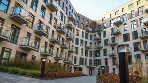Um edifício residencial com várias andares, varandas, um pátio pavimentado e um caminho.