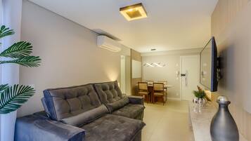 Uma sala de estar moderna com um sofá, um espaço de refeições e uma televisão de tela plana fixada na parede.