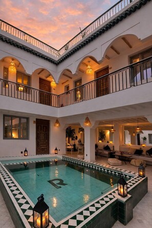 Um edifício com vários andares, piscina central, varandas e áreas de estar internas.