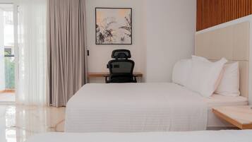 Quarto de hotel com uma cama grande, uma escrivaninha com cadeira, uma janela com cortinas e uma obra de arte pendurada na parede.