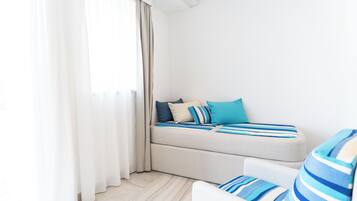 Quarto moderno com sofá-cama, janela com cortinas e almofada listrada.