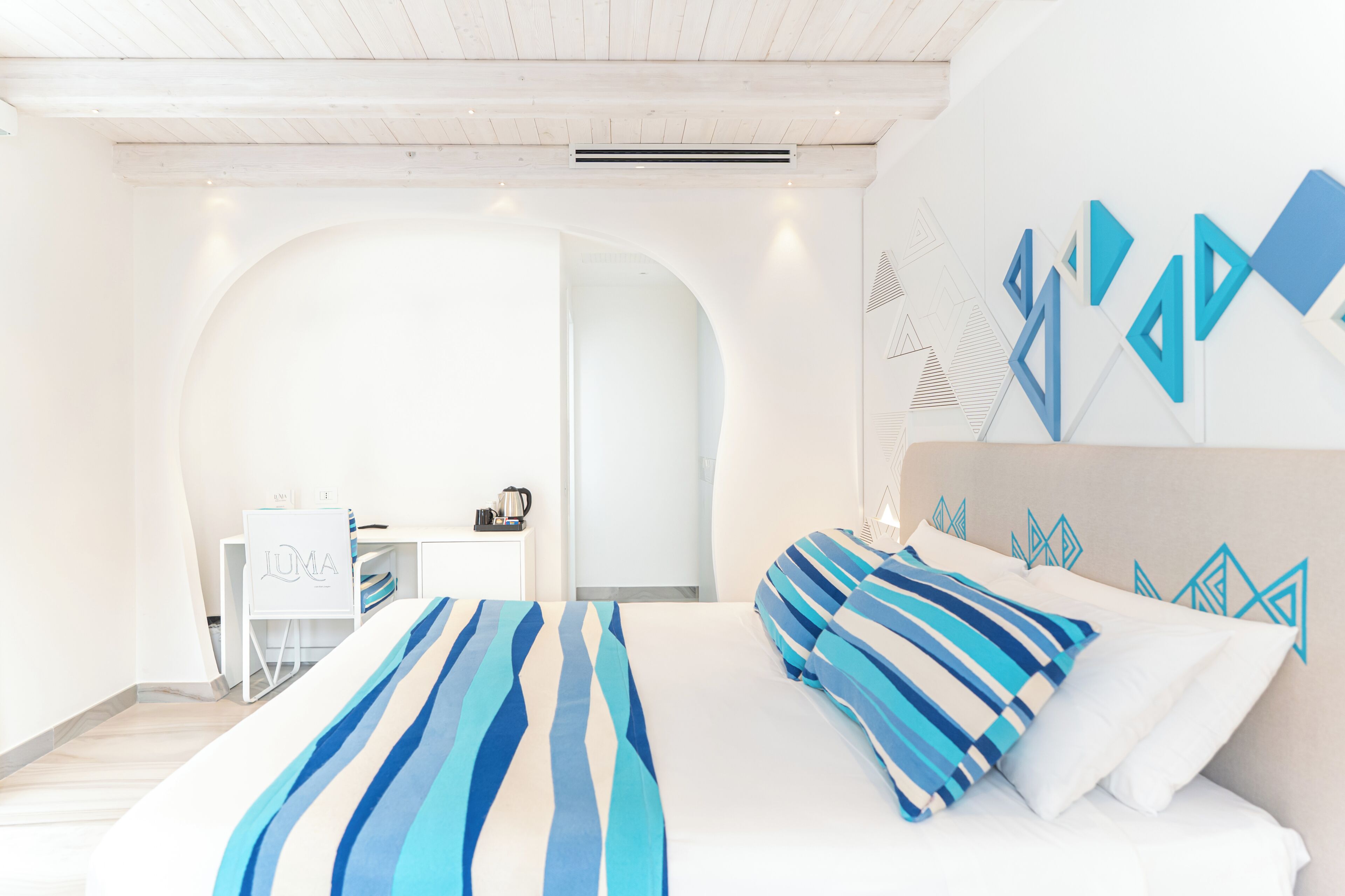 Quarto de hotel moderno com cama, escrivaninha e guarda-roupa branco.