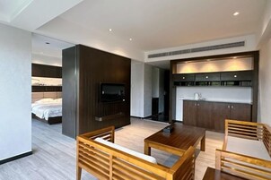 Quarto de hotel moderno com área de refeições, TV fixada na parede e uma kitchenette.