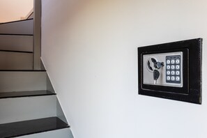 Teclado de segurança numa parede branca ao lado de uma escadaria.