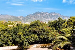 Paisagem montanhosa com vegetação densa em primeiro plano e céu claro.