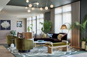 Uma sala de estar moderna com um sofá, poltronas, uma mesa de centro e um candelabro.