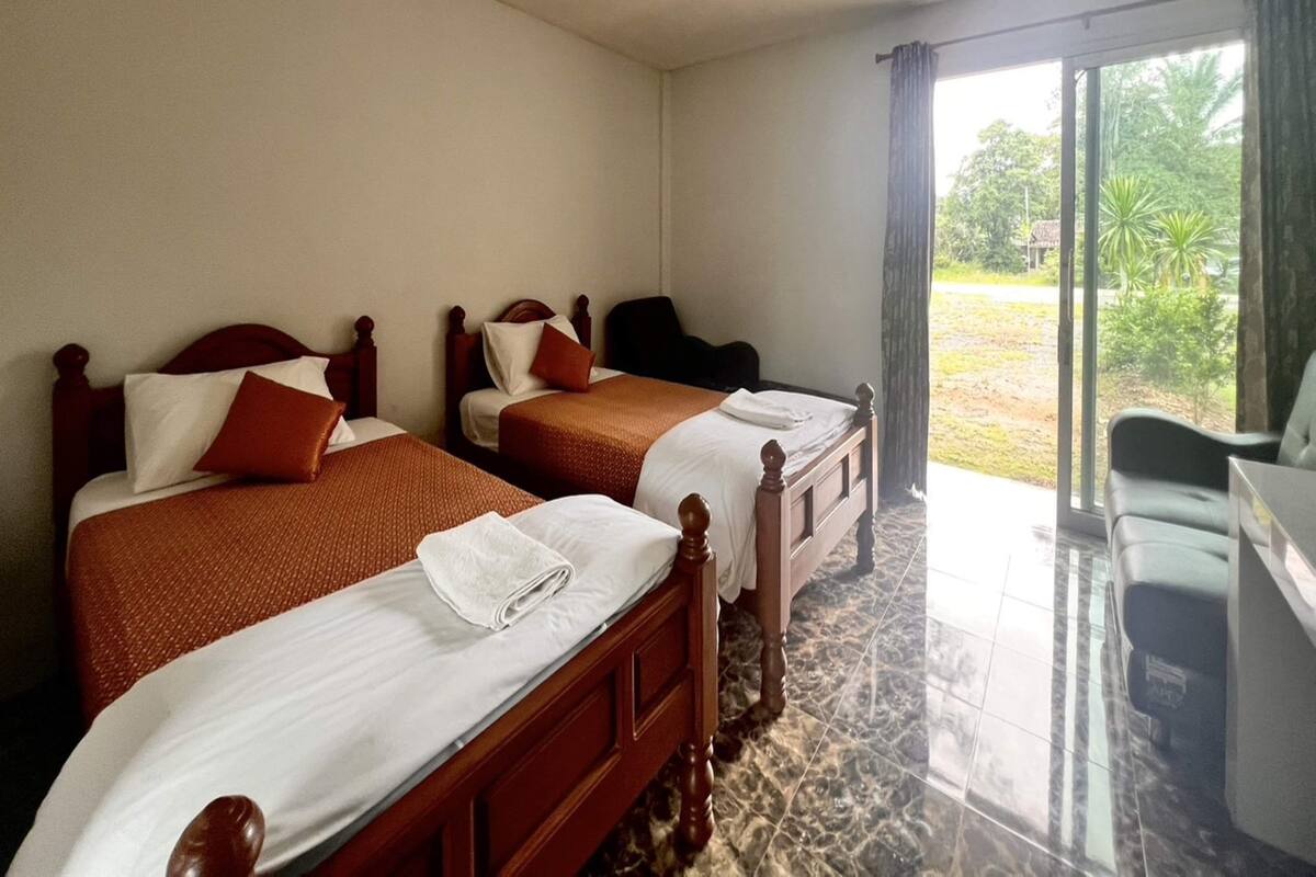 Quarto de hotel com duas camas, uma escrivaninha e vista para o exterior.