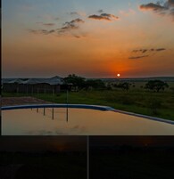 Vista do pôr do sol de uma área de piscina externa, com deck de madeira e cerca.