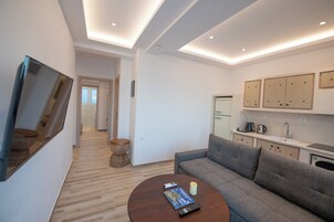 Uma sala de estar moderna com sofá, mesa de centro e área de cozinha com armários e pia.