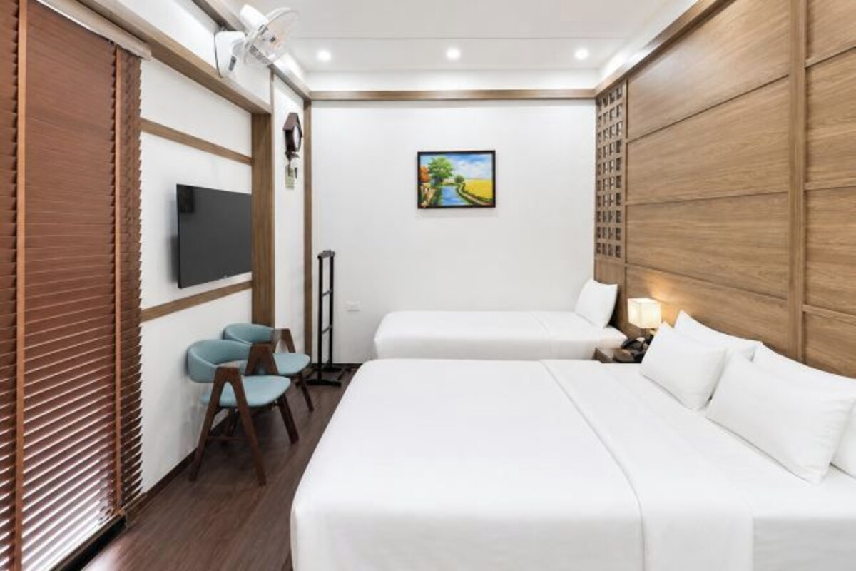 Quarto de hotel com uma cama grande, televisão, secretária e cadeira.