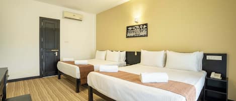 Quarto de hotel com duas camas, ventoinha no teto, aparelho de ar condicionado, obra de arte pendurada na parede e telefone ao lado da cama.