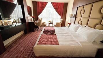 Quarto de hotel com uma cama grande, televisão, escrivaninha e uma cadeira.