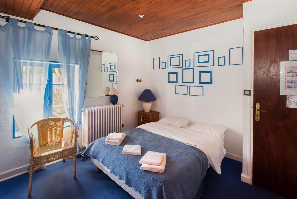 Quarto com cama, uma cadeira, radiador e decorações nas paredes.