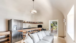 Cozinha moderna com frigorífico embutido, bancada de madeira e área de refeições.