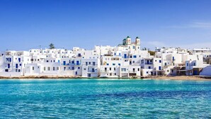 Uma vila costeira com edifícios brancos e mar azul cristalino.
